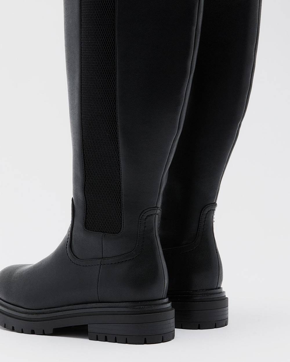 Bottes hautes noires à talon plat et bande élastique sur le côté, pied ...